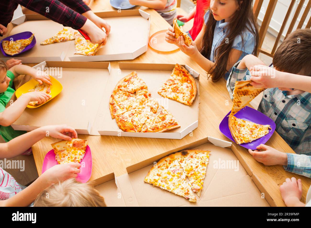 Happy children eating pizza enjoying birthday party in cafe Stock Photo ...
