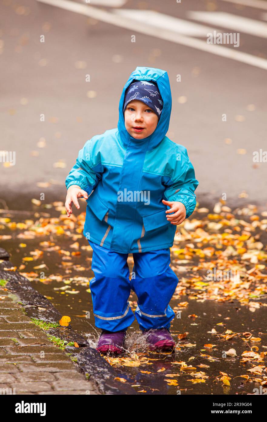 Happy child jumping in puddle in autumn time Stock Photo - Alamy