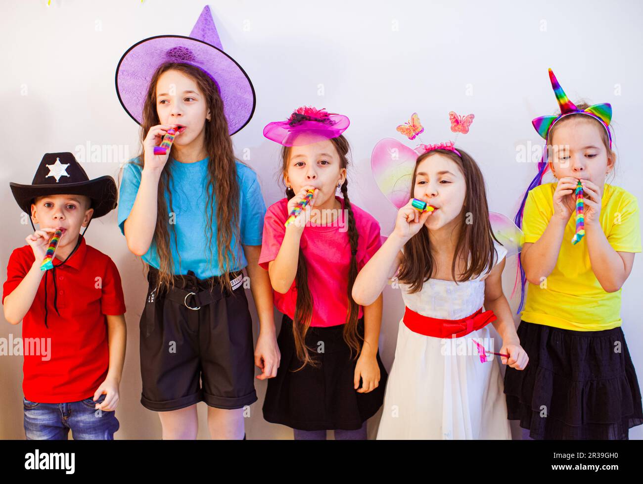 Adorable kids having fun at birthday party. Friends blowing whistles ...