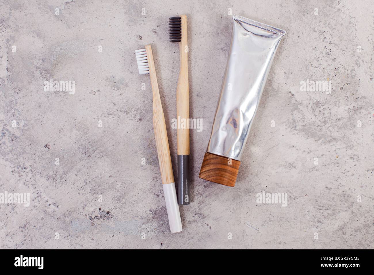 Bamboo teeth brushes and tube of toothpaste on minimalistic concrete ...