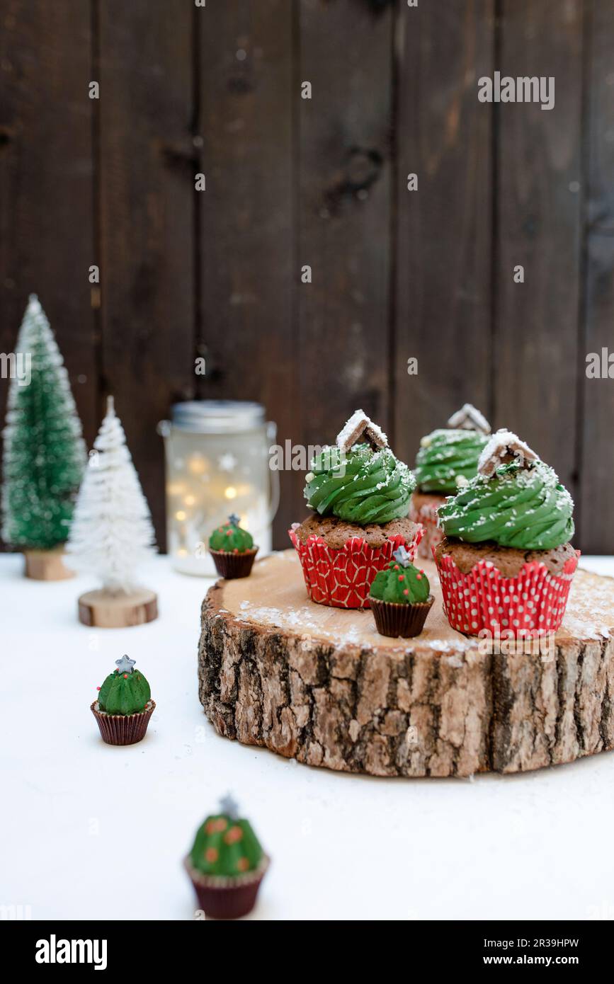 Christmas chocolate muffins with creamy green frosting on a log slice ...