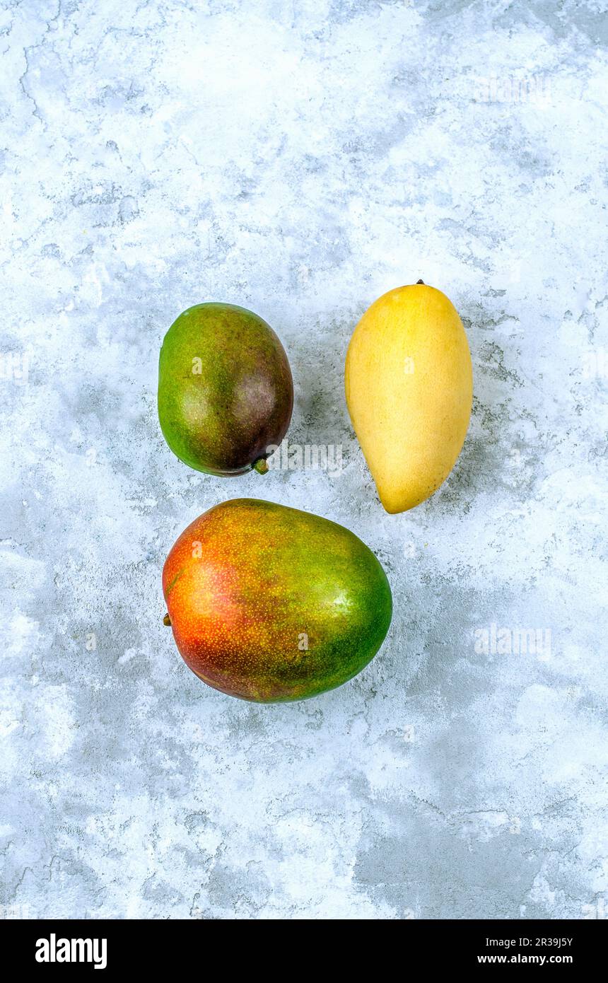 Three mangoes of different varieties, is laid out in a triangle on a ...