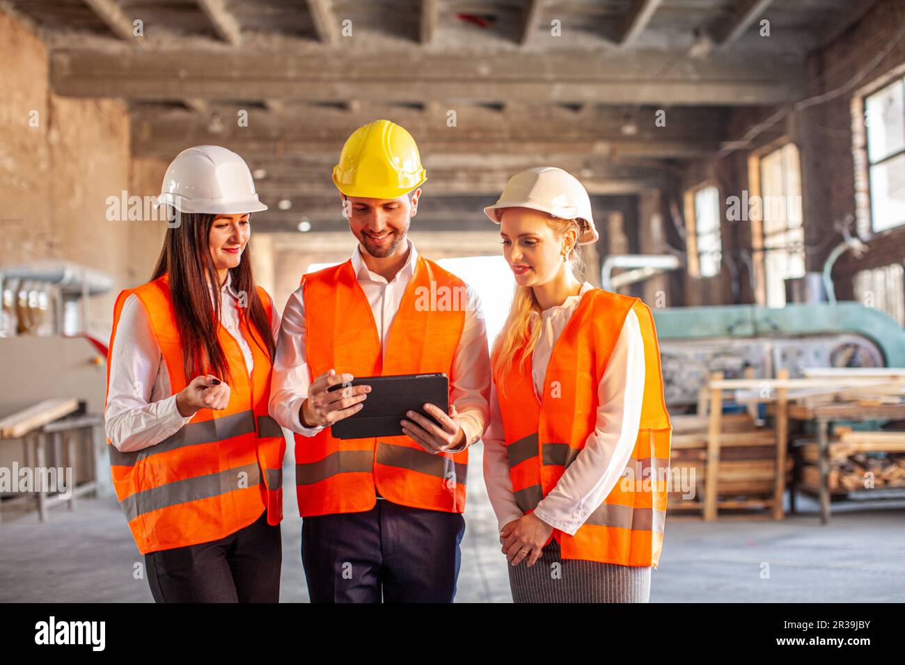 Team of young construction workers discussing project details with ...
