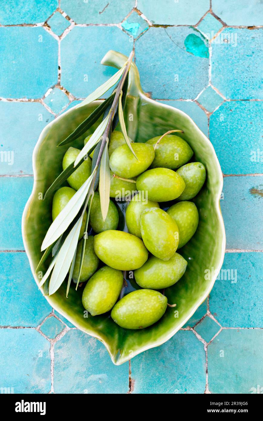 Green olives with a branch in a ceramic bowl Stock Photo - Alamy