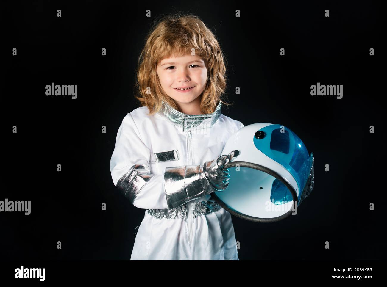 Cute little boy spaceman child in space suit holding helmet on black ...