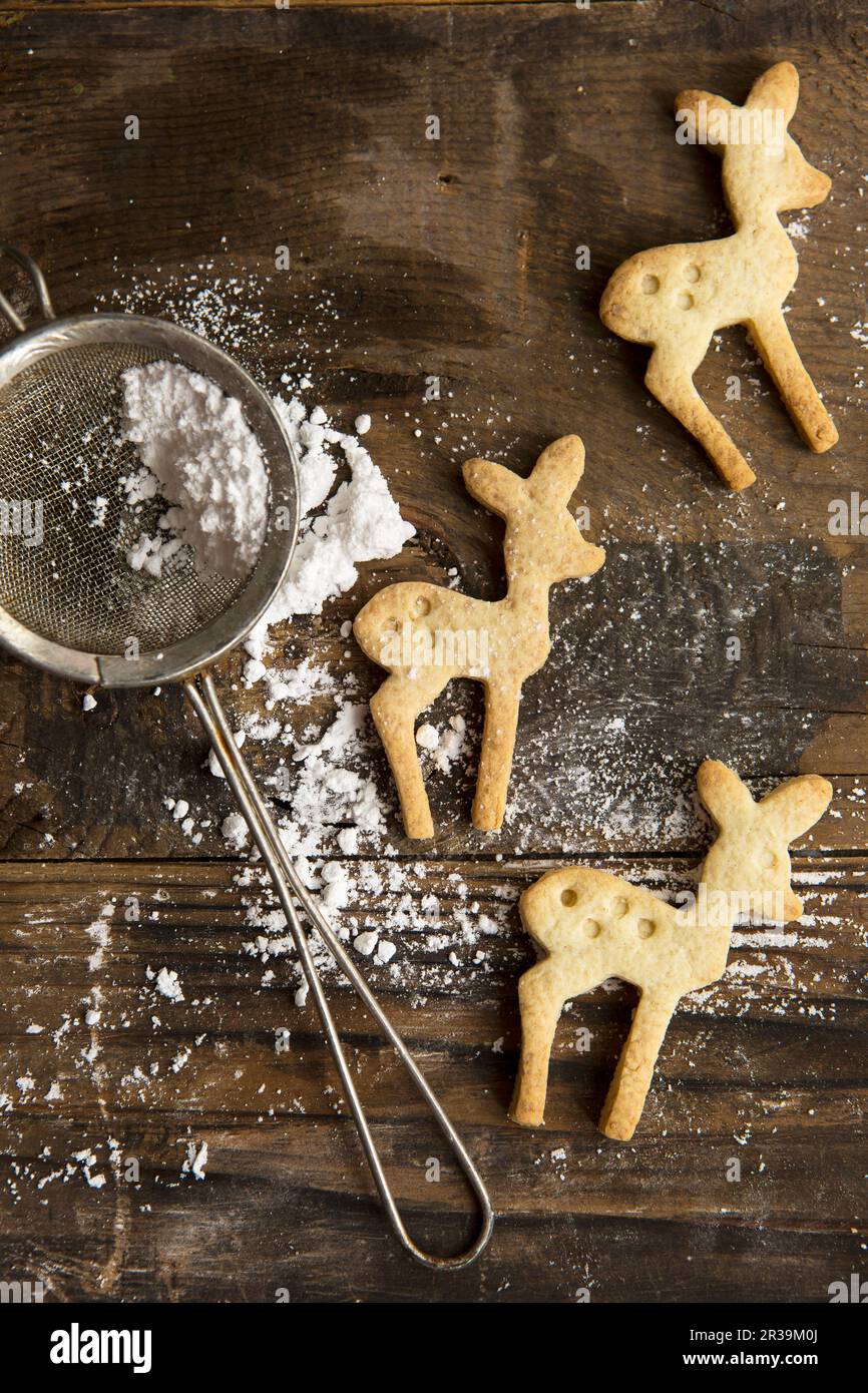 Three Festive Christmas Deer shaped cookie biscuits on a rustic board ...