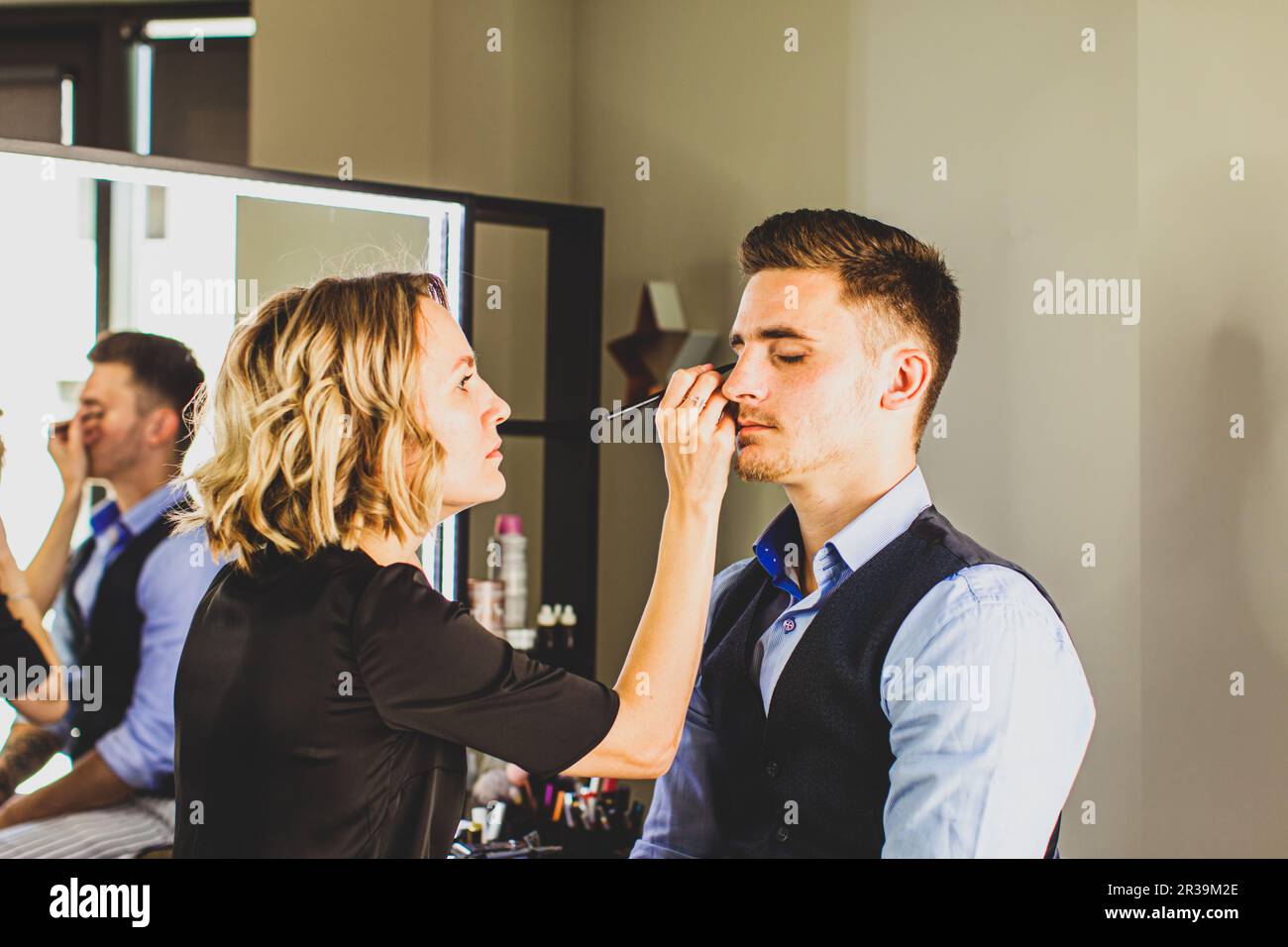 Makeup artist doing professional makeup for young man Stock Photo - Alamy