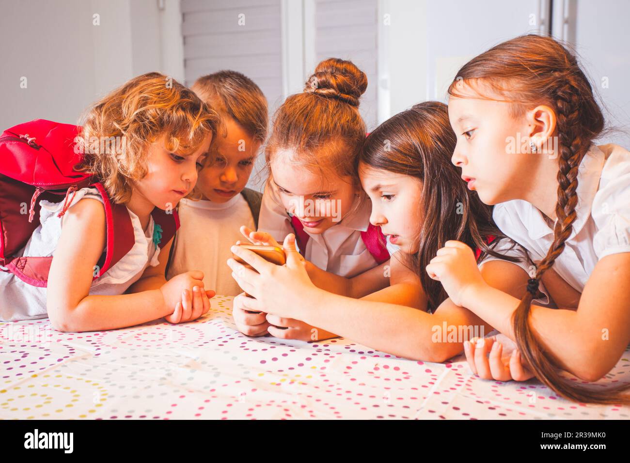 Group of school kids with smartphone having fun on break in classroom ...