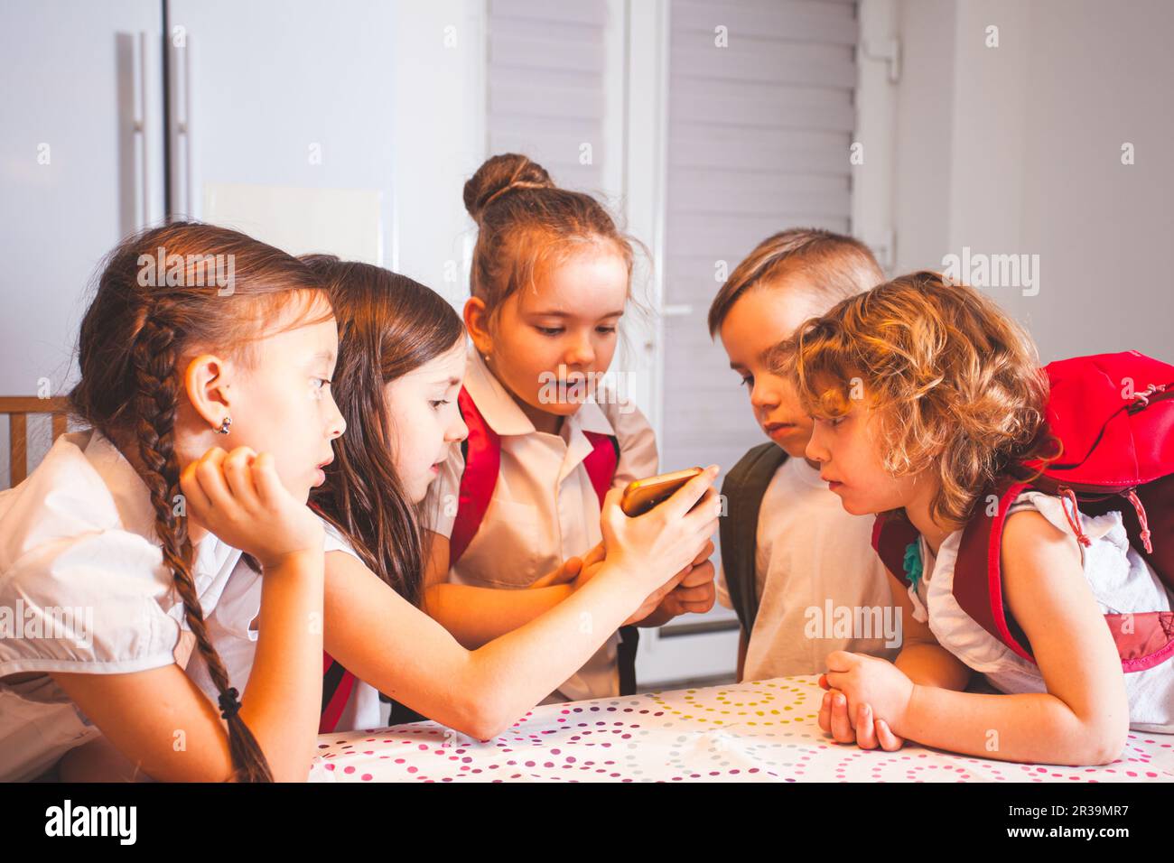 Cute pupils talking and using smartphone during break. Happy friends ...