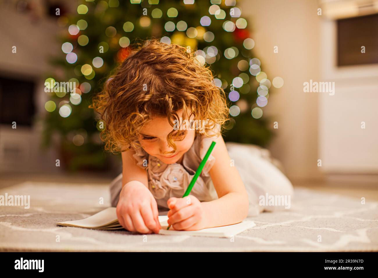 Little curly girl writing letter on the floor Stock Photo - Alamy
