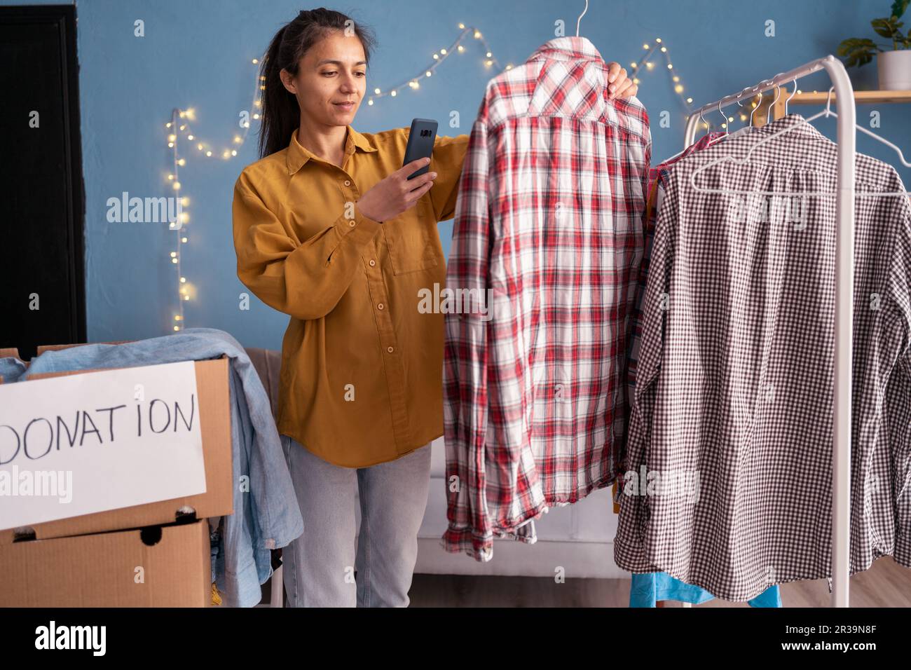 Business woman choose clothes for donation, take photos of shirts using ...