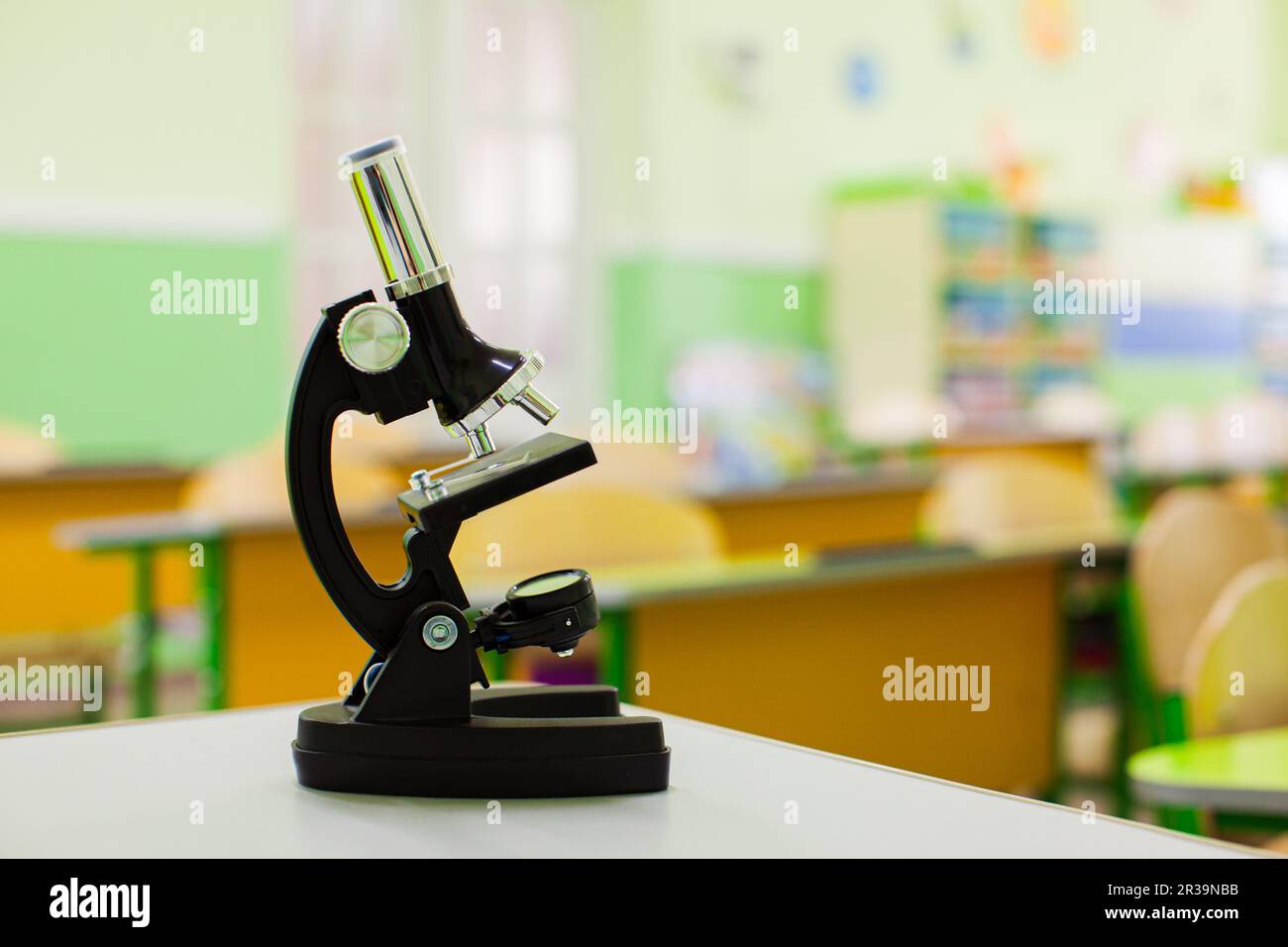 Black microscope on teachers table in empty classroom Stock Photo - Alamy