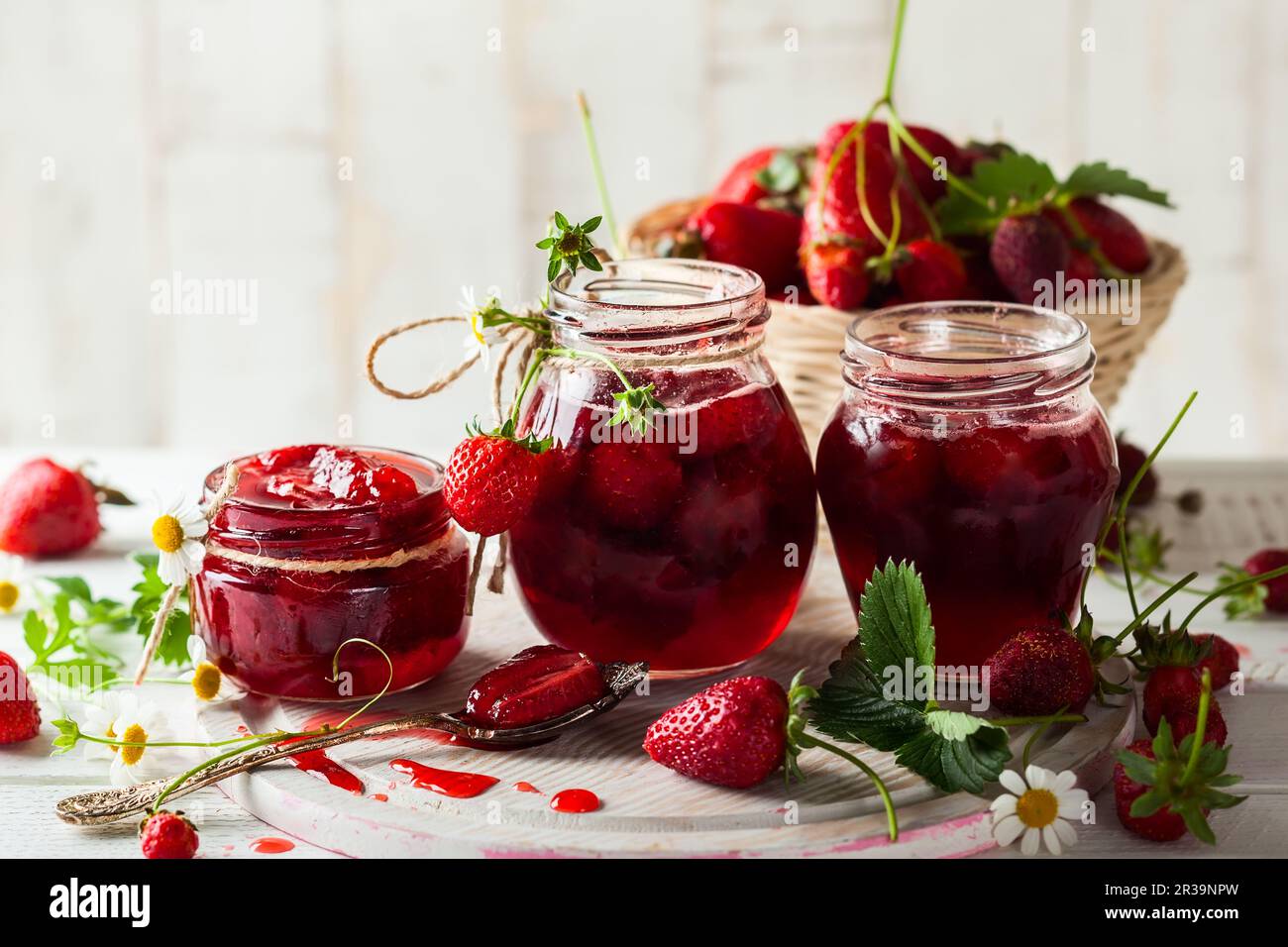 Homemade strawberry jam in glass jars on wooden board in rustic style ...