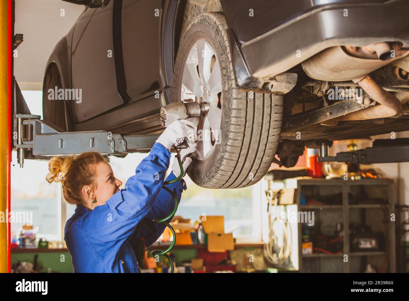 Female tyre service worker fixing wheels on lifted car Stock Photo - Alamy