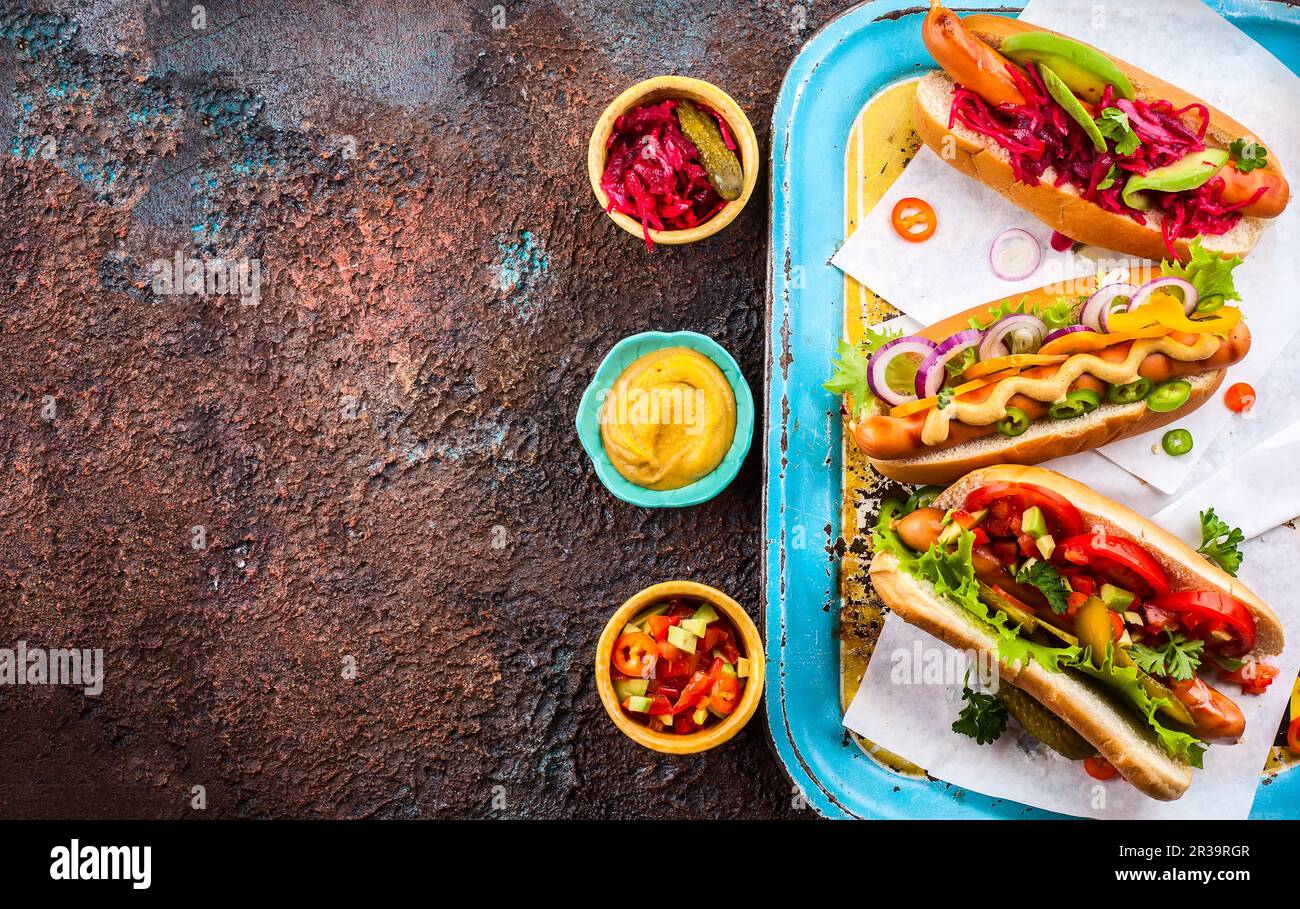 Variety of delicious hot dogs with vegetables and sauces on a vintage ...
