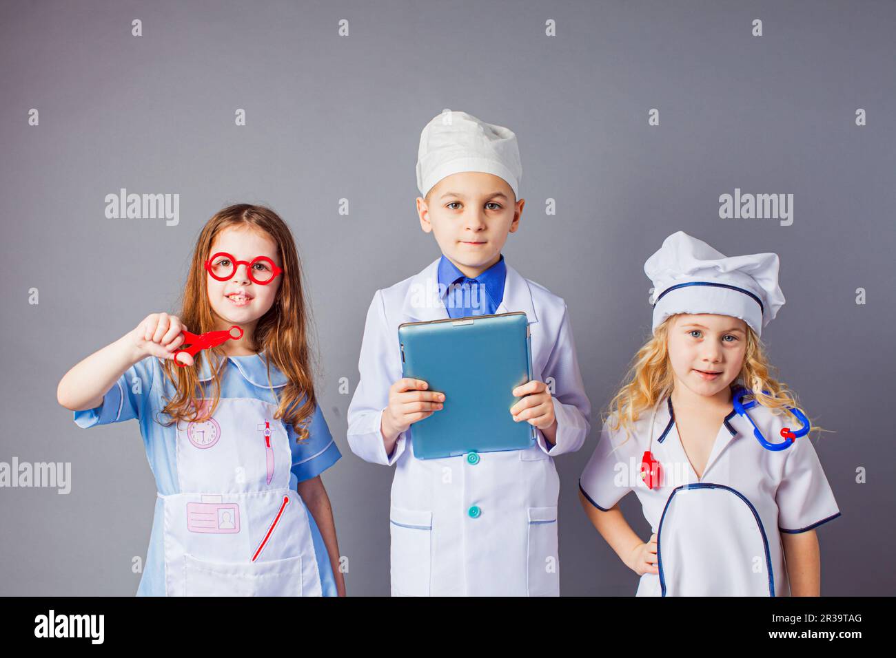 Cute little children dressed as doctors on grey background Stock Photo ...