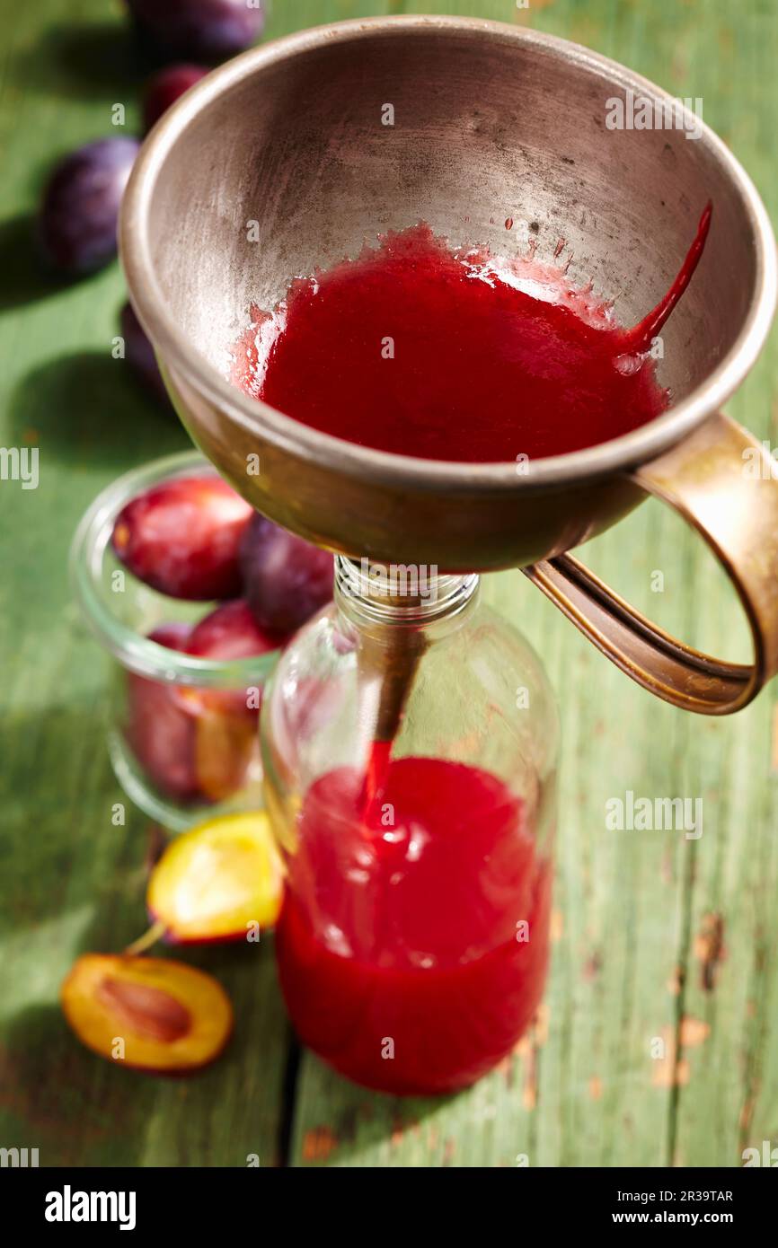 Homemade damson syrup being poured into a bottle using a funnel Stock ...
