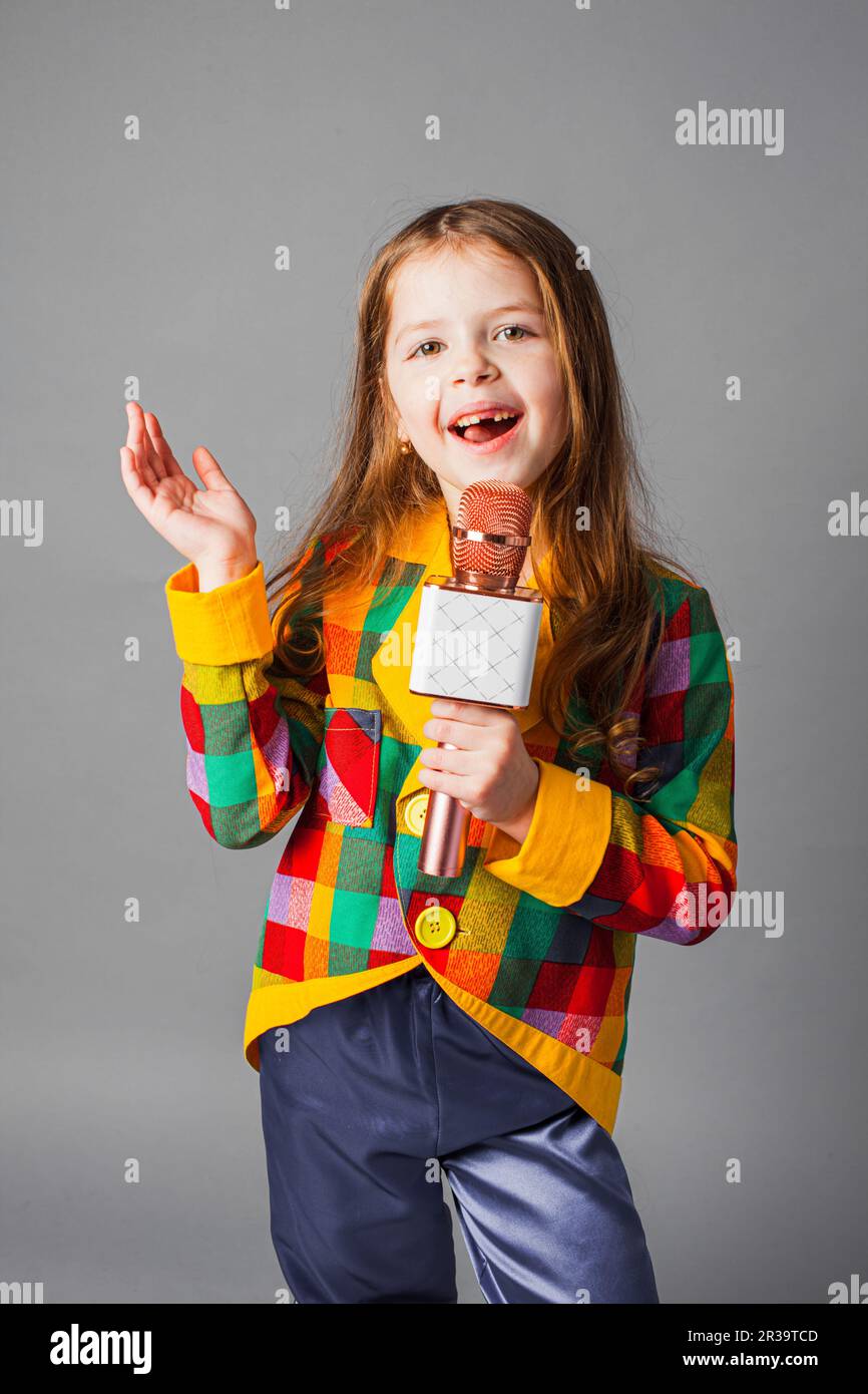 Little singer girl. Little girl with microphone over grey background ...