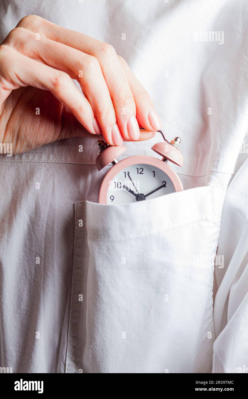 Woman with alarm clock spends time carefully Stock Photo - Alamy