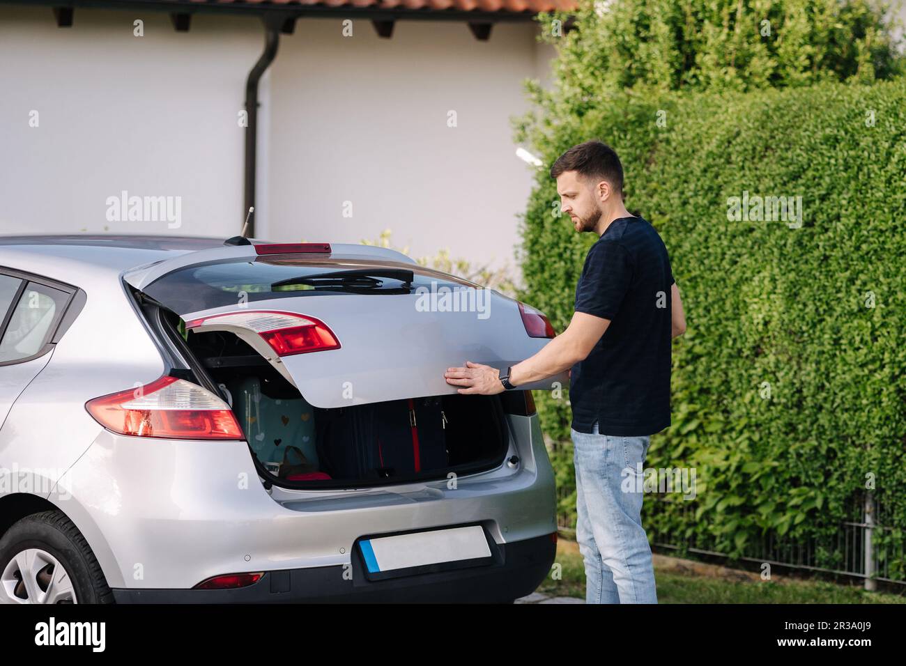 Side view of handsome man open hatchback car for trunk. Vehicle and ...