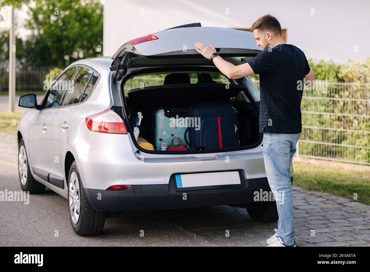 Side view of handsome man close hatchback car for trunk. Vehicle and ...