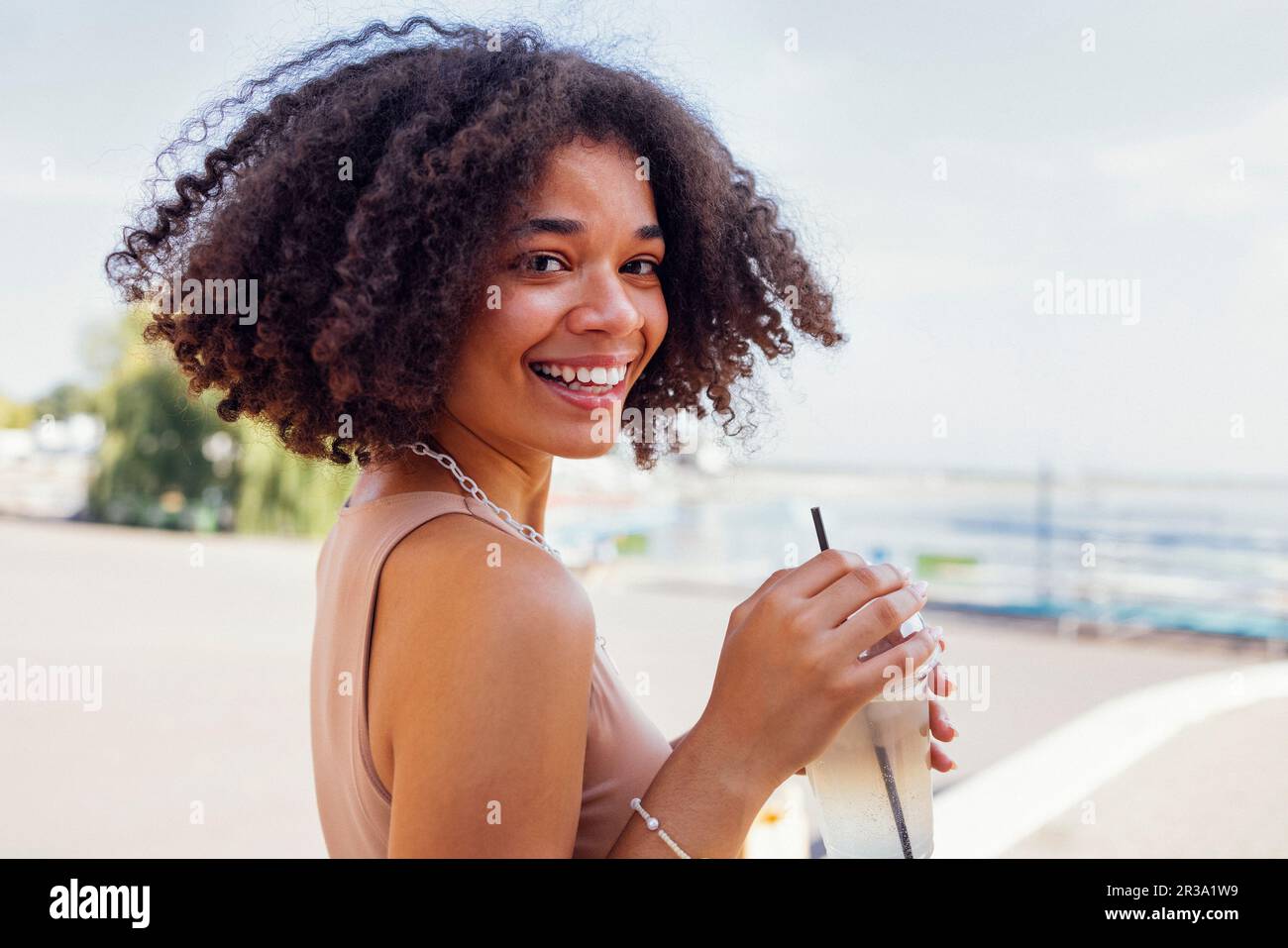 Happy african american teen girl drinking lemonade in open air cafe ...