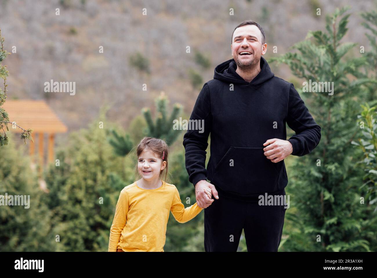 Young laughing man holds the hand of little cute girl. Smiling dad together with his sweet ...