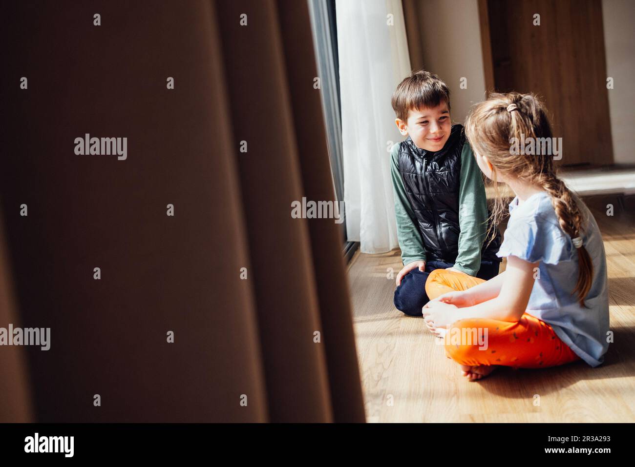 Cute children in casual clothes are sitting on the floor near the ...
