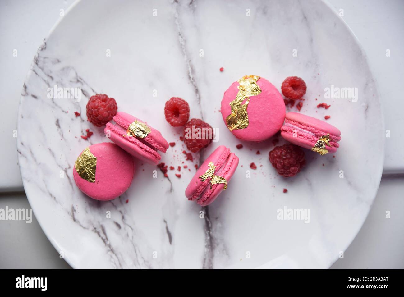 Raspberry macaroons with gold leaf and fresh raspberries Stock Photo ...