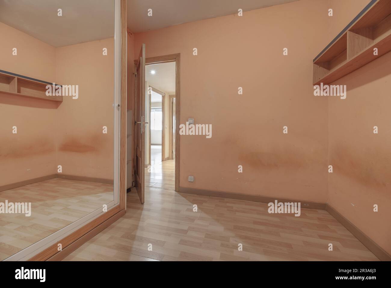 A room with dirty walls painted in peach color and a large built-in ...
