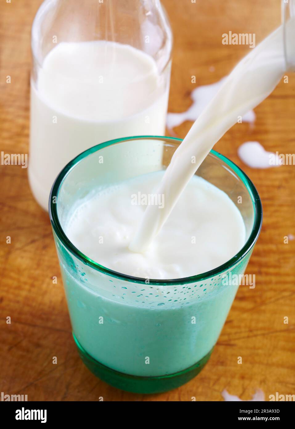 Milk being poured into a green glass Stock Photo - Alamy