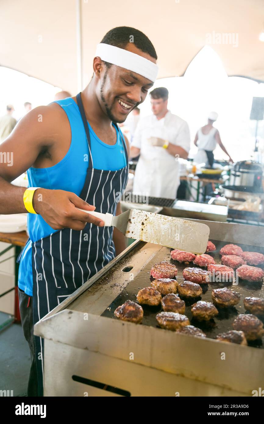Chef making and serving take-away meals at food festival vendor stall ...