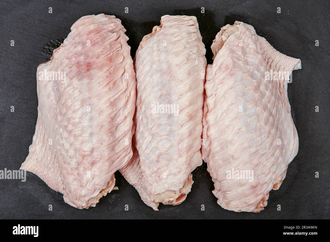 Raw turkey wings on black Slate Tray. Fresh turkey wingette on a black ...