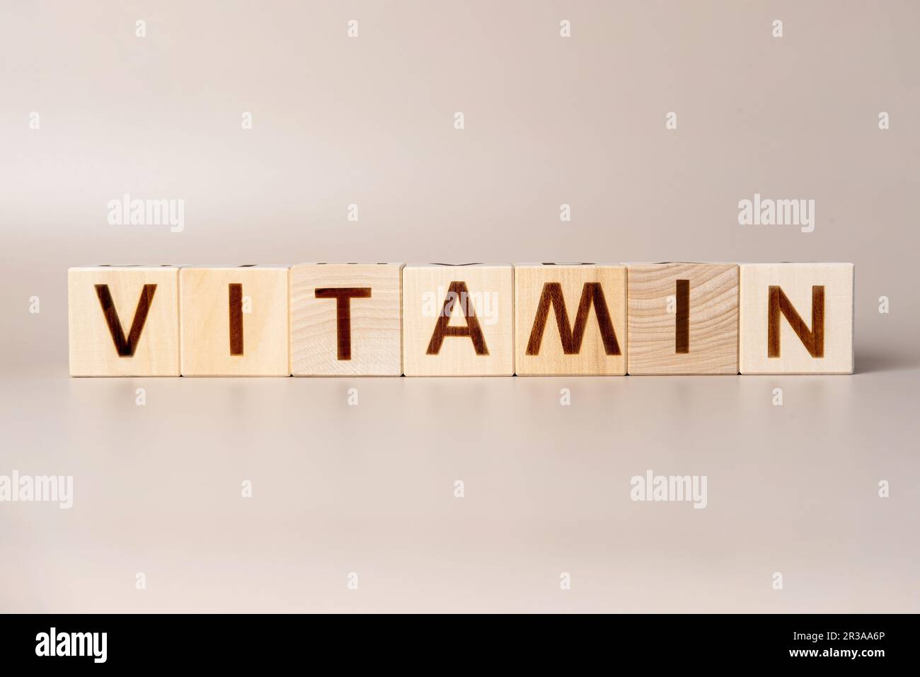 The word VITAMIN on wooden cubes on a beige neutral studio background ...