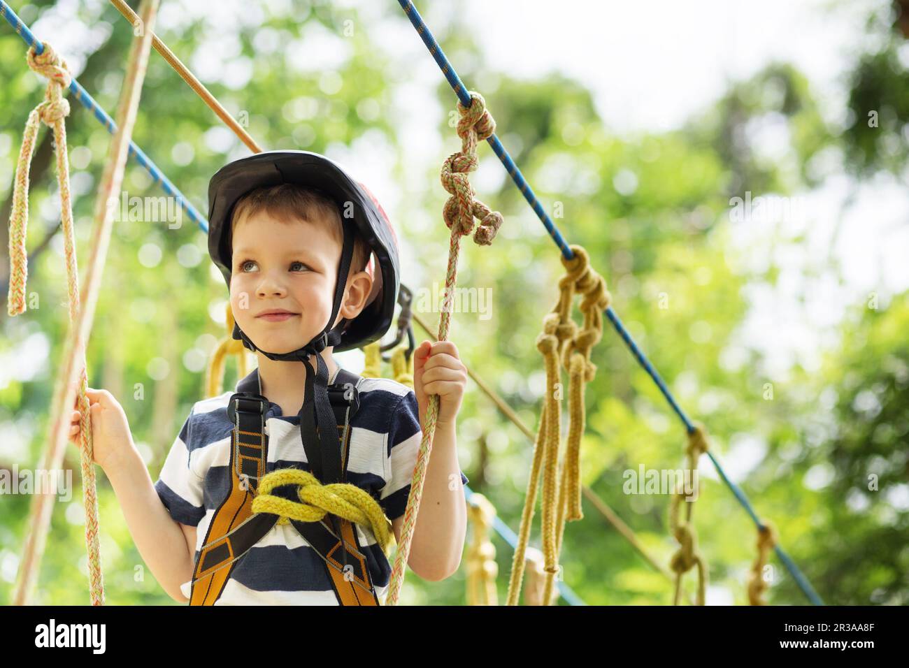 Kids climbing in adventure park. Boy enjoys climbing in the ropes ...