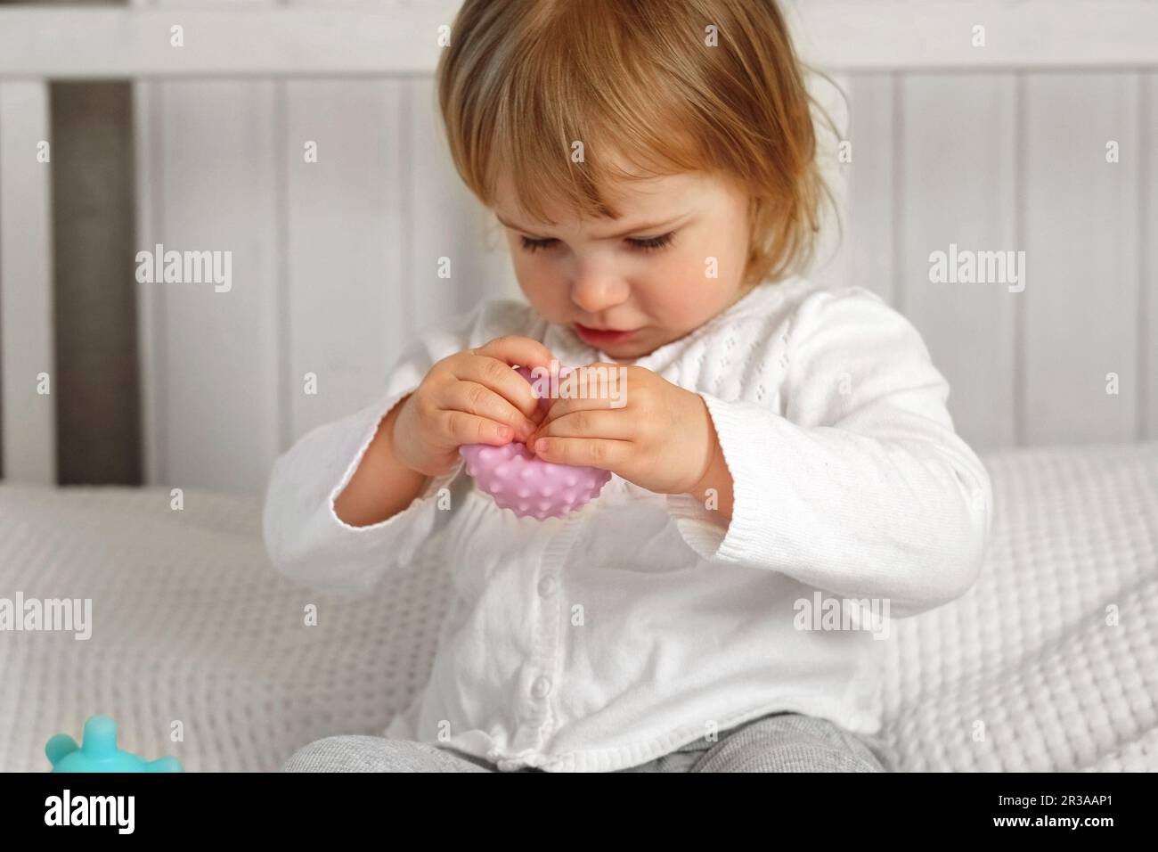 Cute baby girl playing tactile knobby balls. Young child hand plays ...