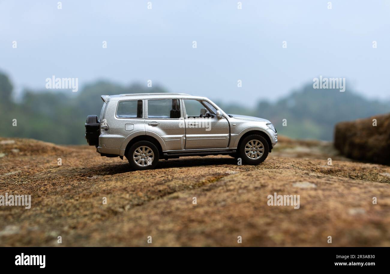 Concept for traveling and adventure. A toy car on a giant rock, after ...