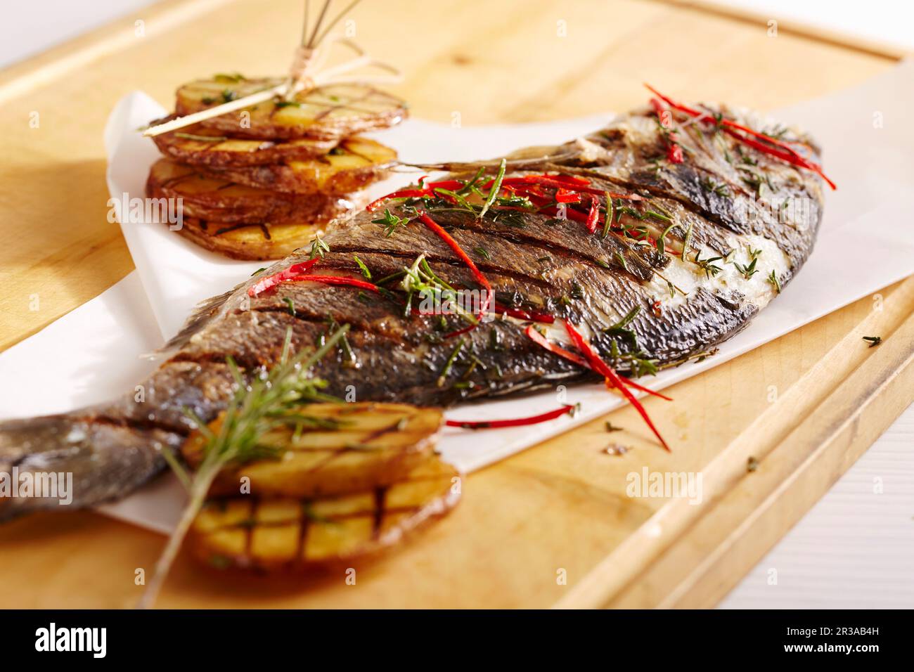 A whole, grilled bream with jalapenos, herbs and potatoes Stock Photo ...