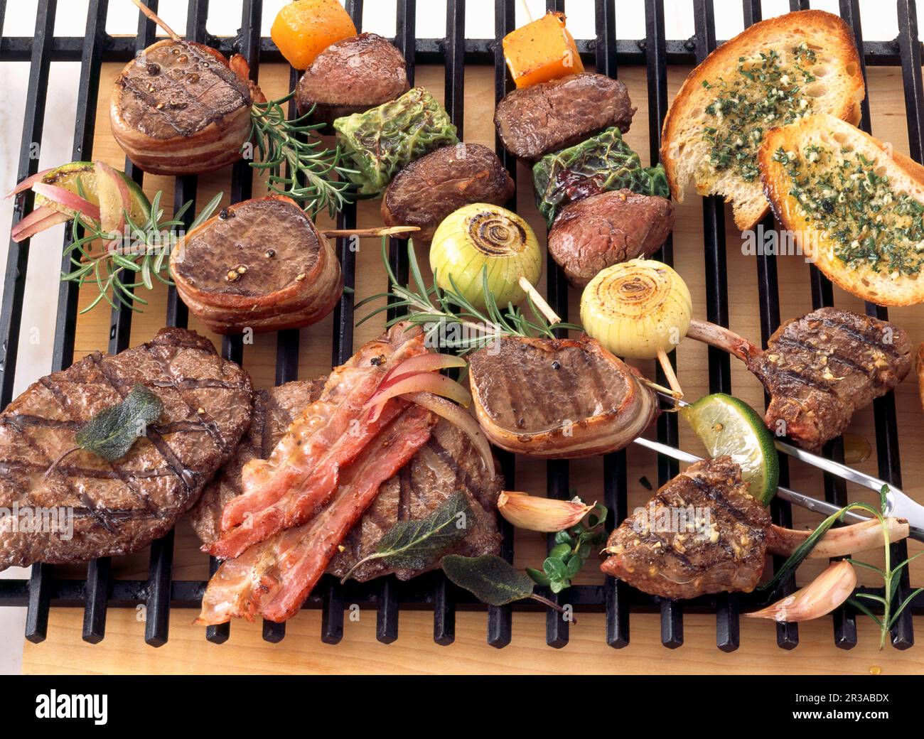 Various game meats and vegetables on a grill rack Stock Photo - Alamy