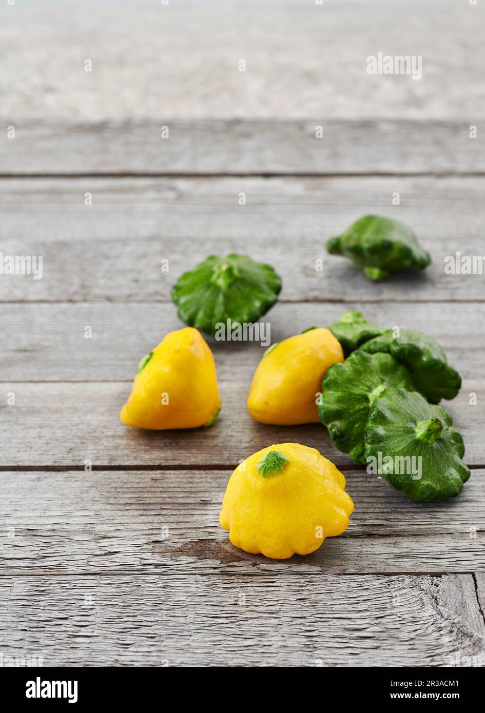 Mini yellow and green patty pan squash on a rustic wooden table Stock ...
