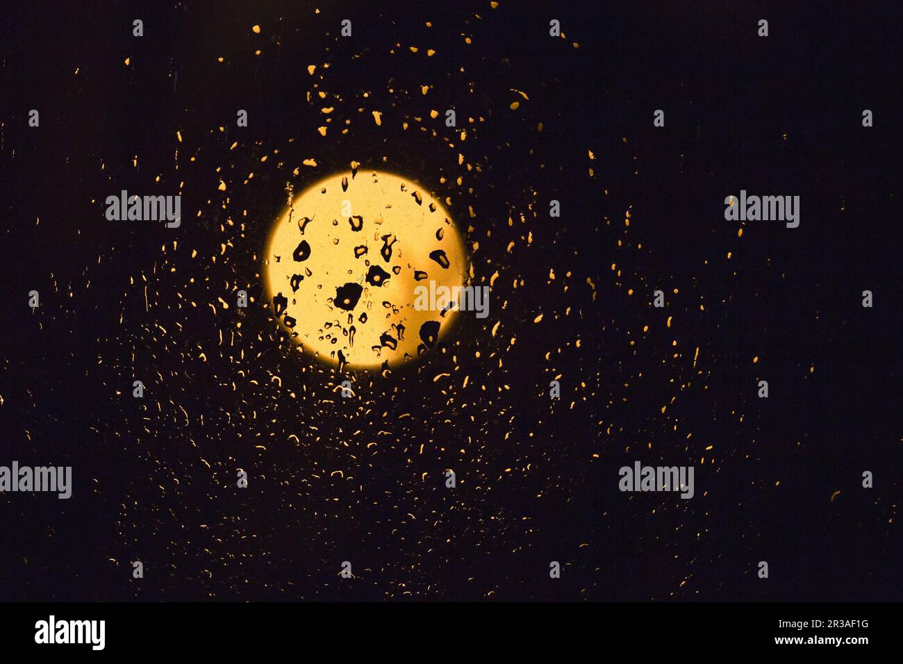 Drops of rain and light of the moon on dark glass at night. Wet window ...