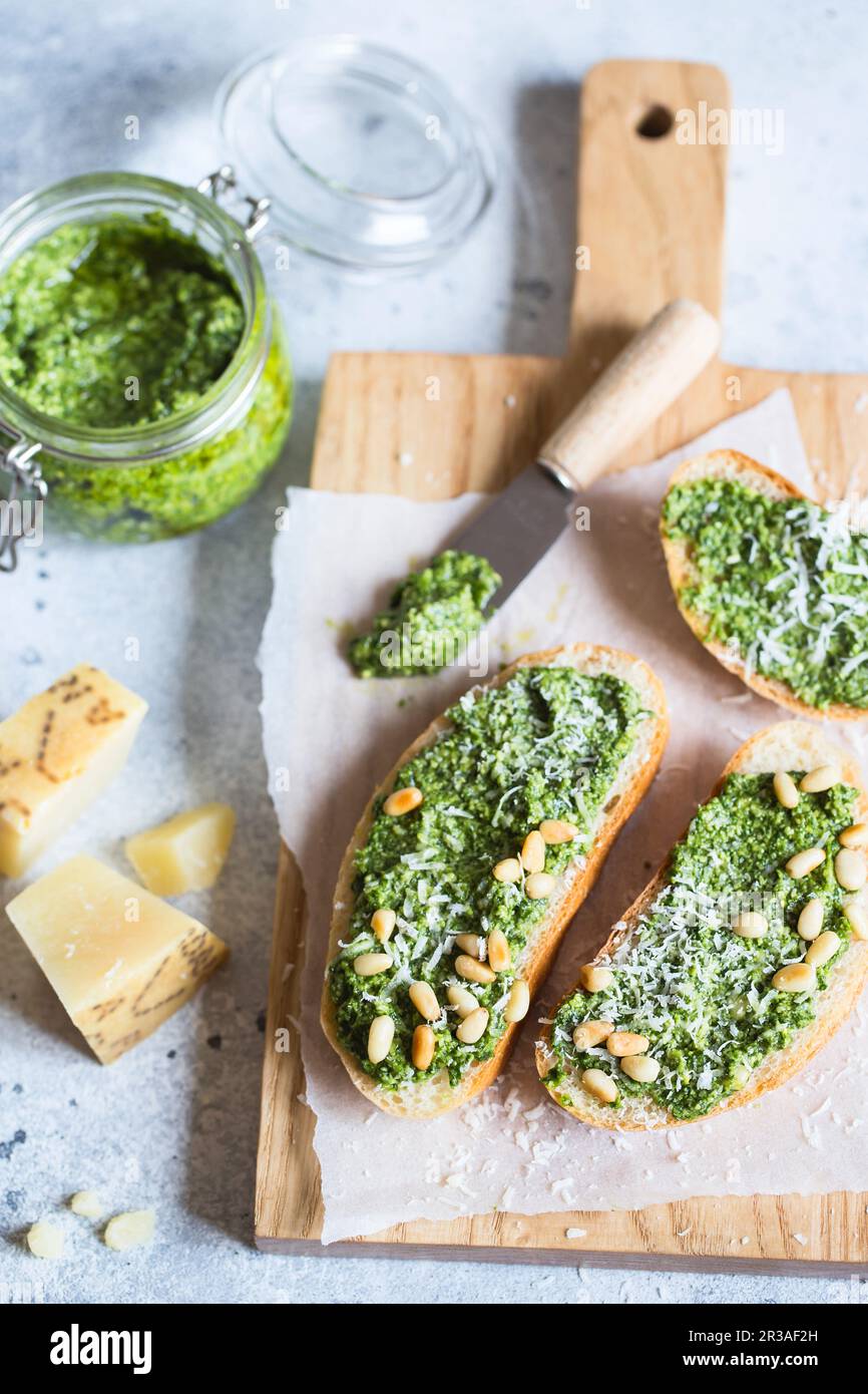 Toasts with traditional Italian basil pesto sauce on a light grey stone ...