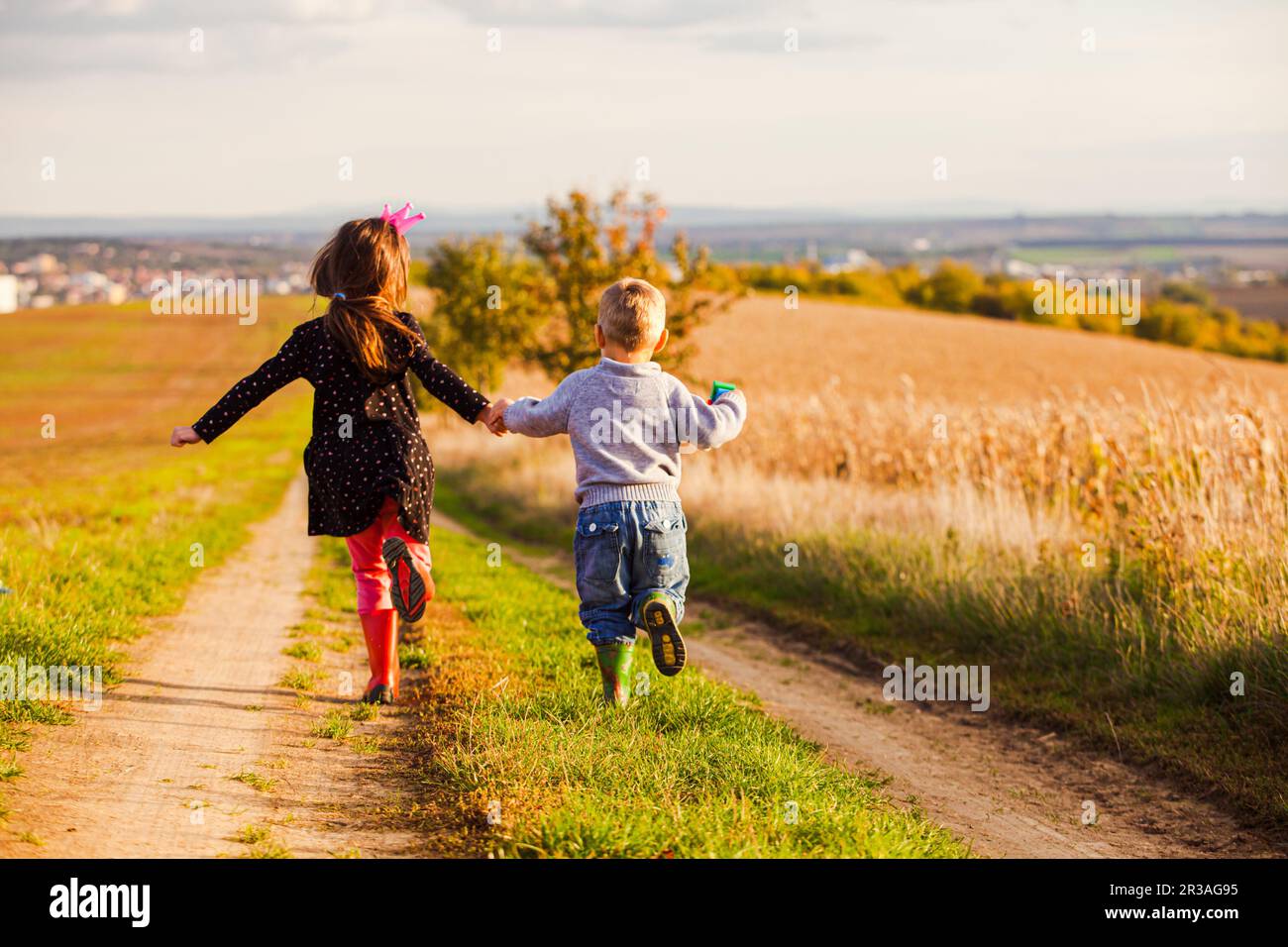 Kids have fun are running on country road Stock Photo - Alamy