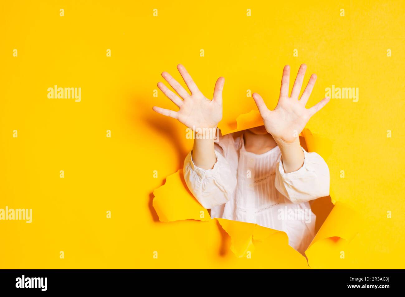Child hands is showing ten fingers through a ripped hole in yellow ...