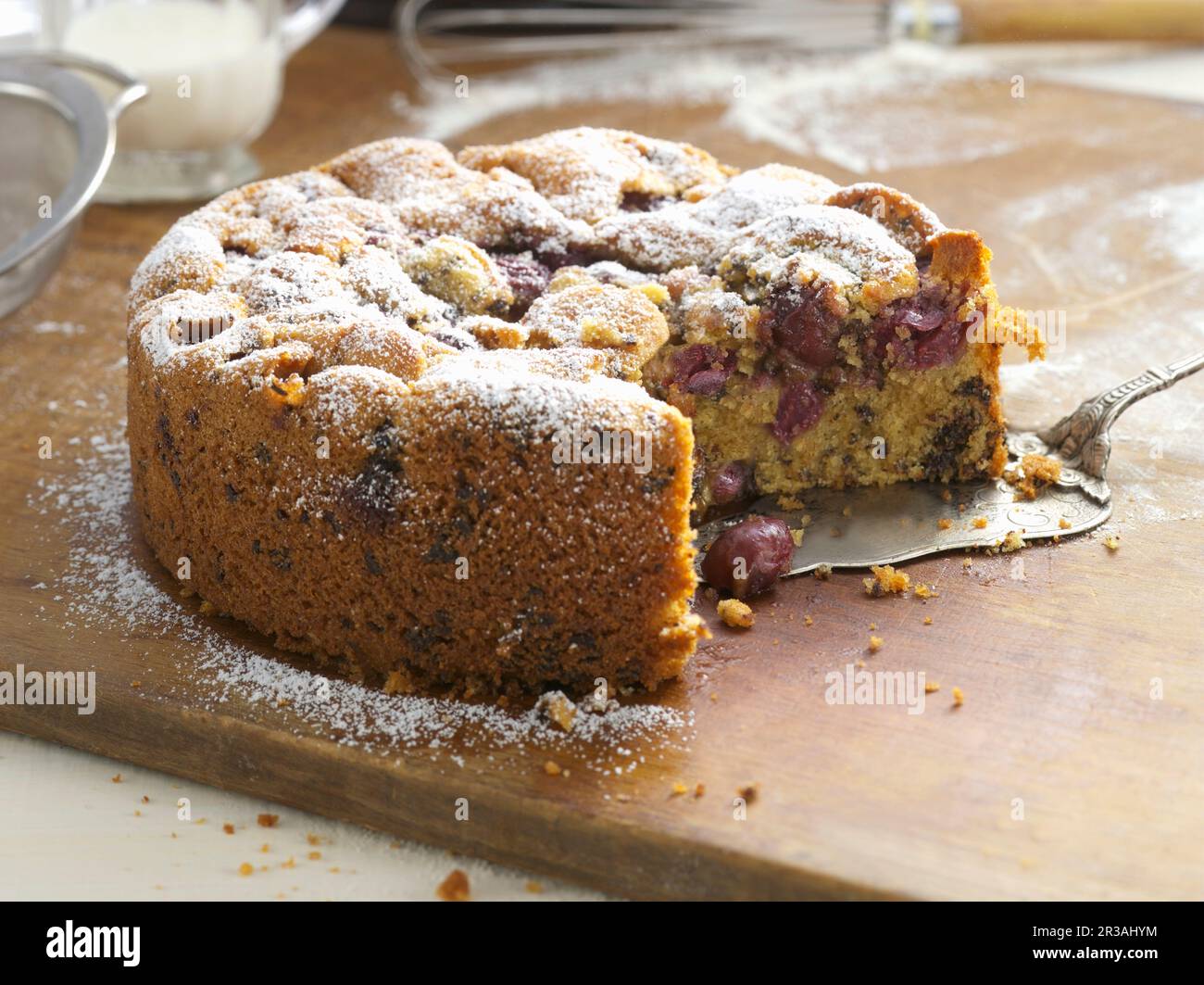 Cherry cake dusted with icing sugar, a piece cut Stock Photo - Alamy