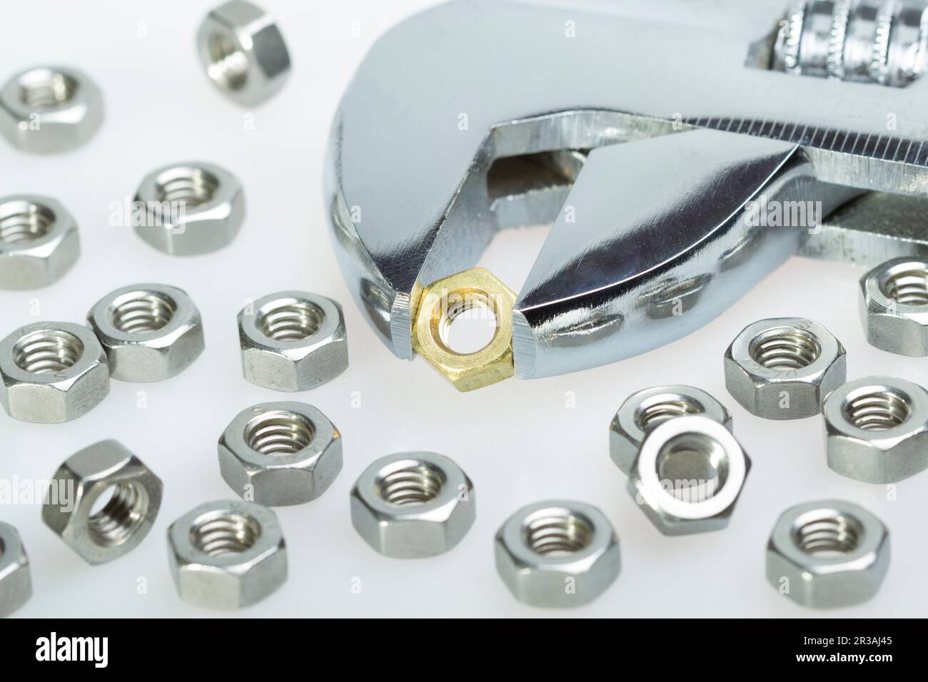 Metallic hex nuts and an adjustable wrench. Steel nuts and one brass ...