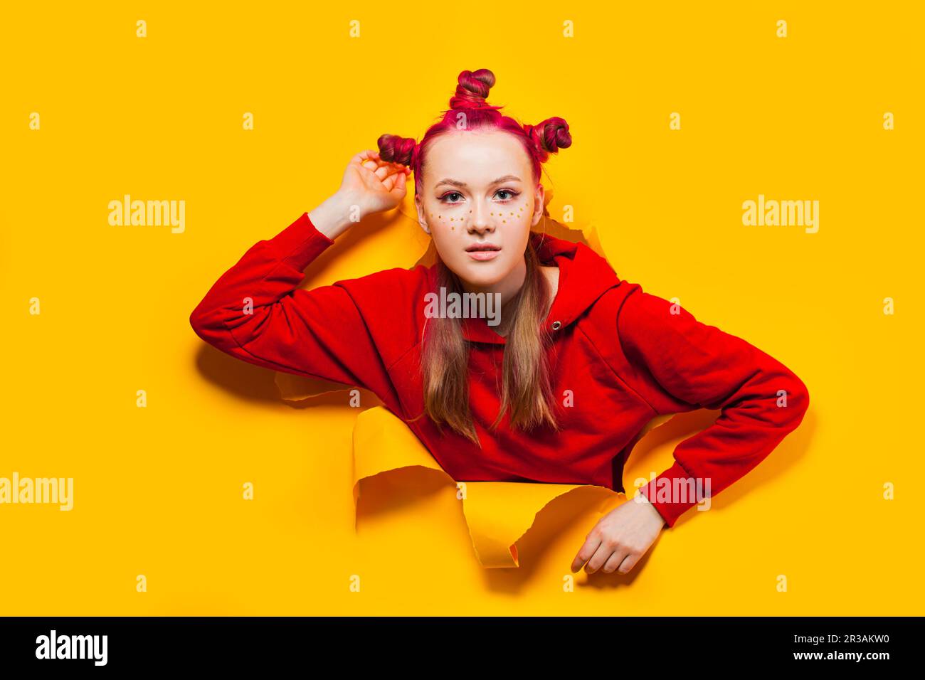 Girl is breaking through color paper wall Stock Photo - Alamy