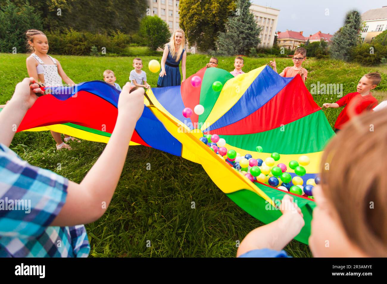 Kids holding rainbow parachute with colorful balls on it Stock Photo ...