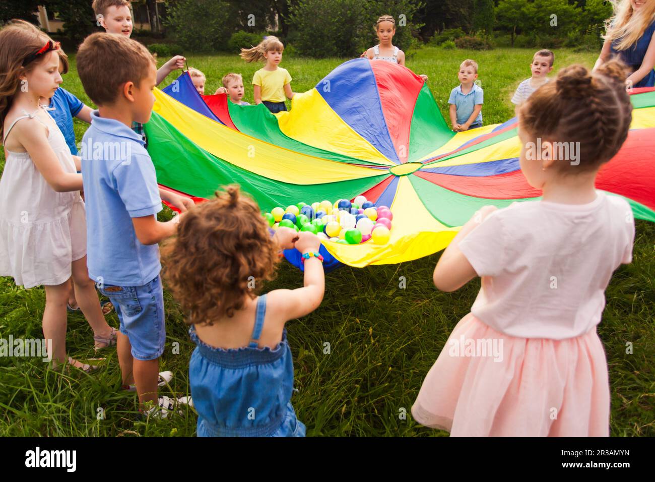 Close view kids around large colored parachute Stock Photo - Alamy