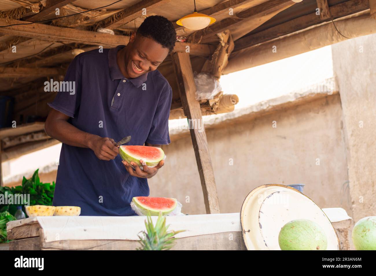 excited young handsome african trader slicing and selling fruit in a ...
